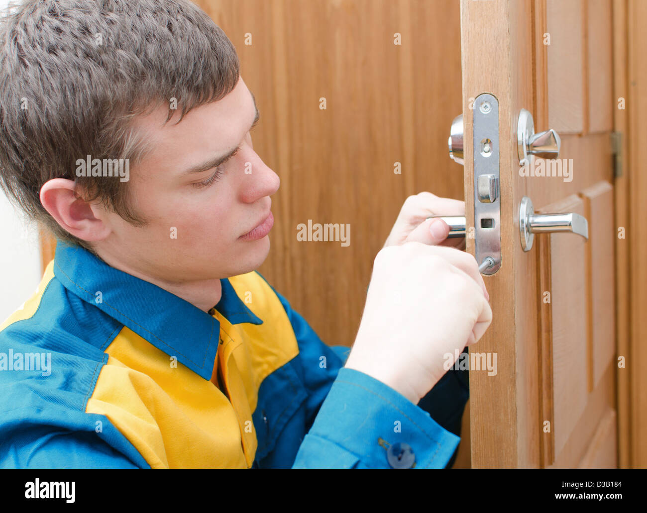 Handyman in uniform changing door lock Stock Photo - Alamy