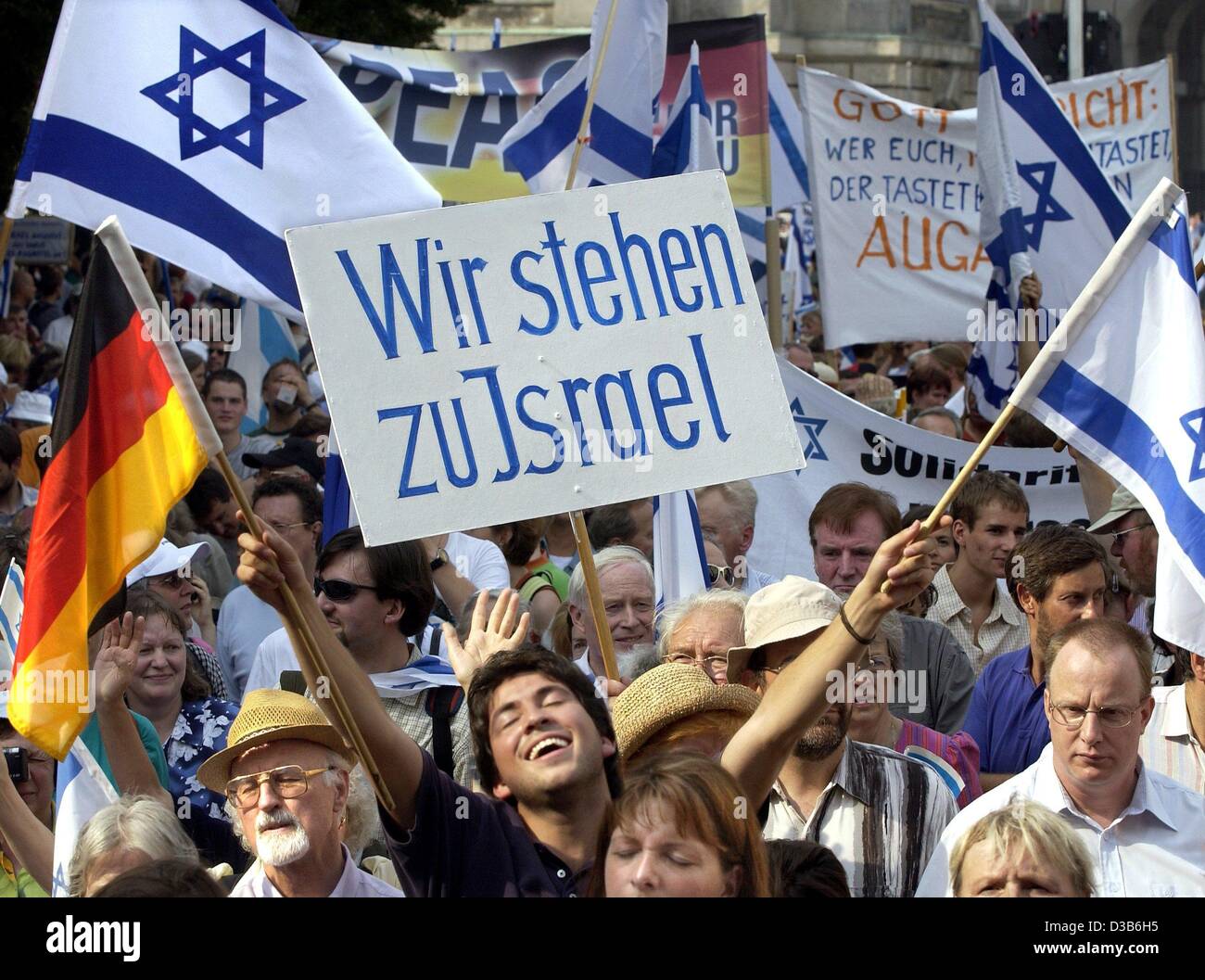 (dpa) - Demonstrators hold up German and Israeli flags and a poster ...