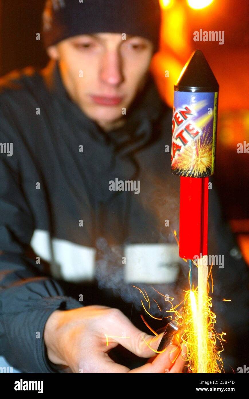 (dpa) - A young man lights the fuse of a firework skyrocket which is ...