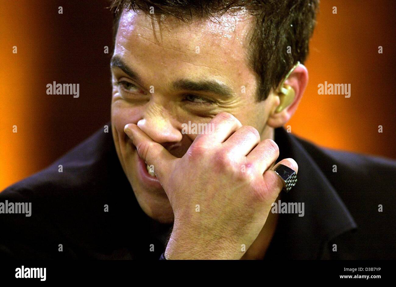 (dpa) - British pop star Robbie Williams rubs his nose during the live ...