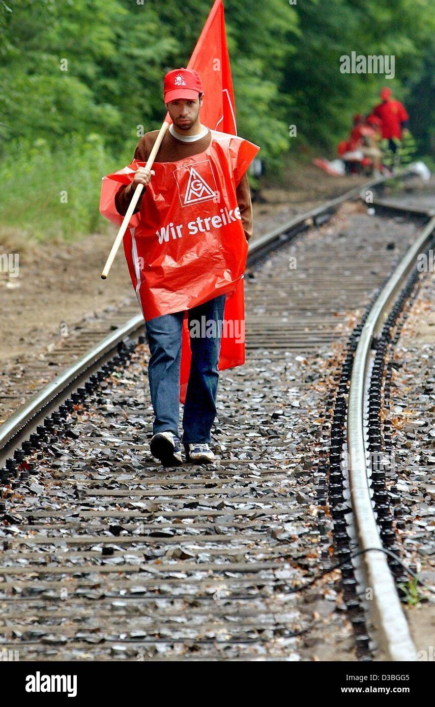 (dpa) - A strike picket is equipped with flag and shirt of the German ...