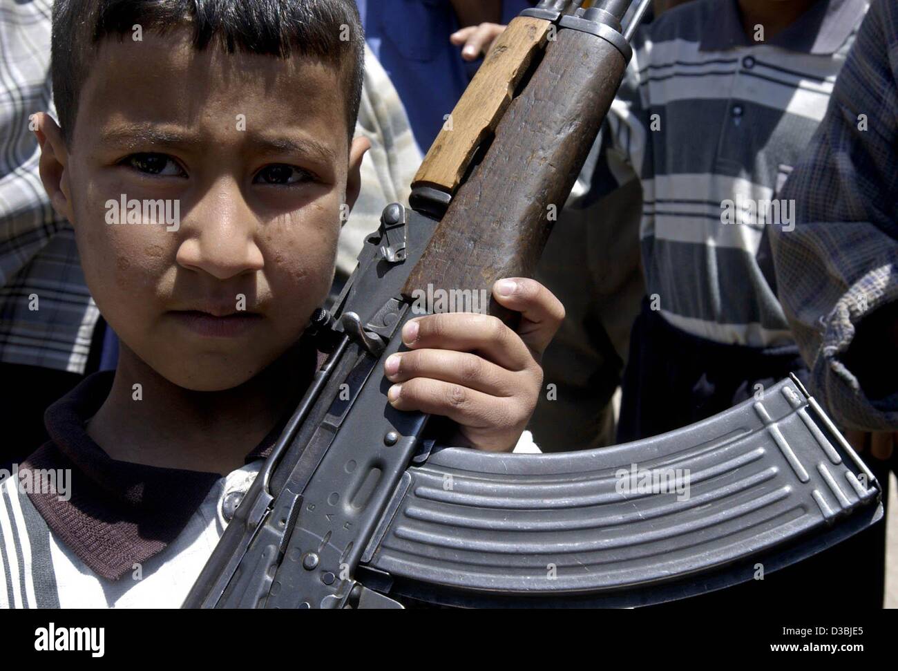 (dpa) - An Iraqi boy holds a machine gun at the weapons market in ...