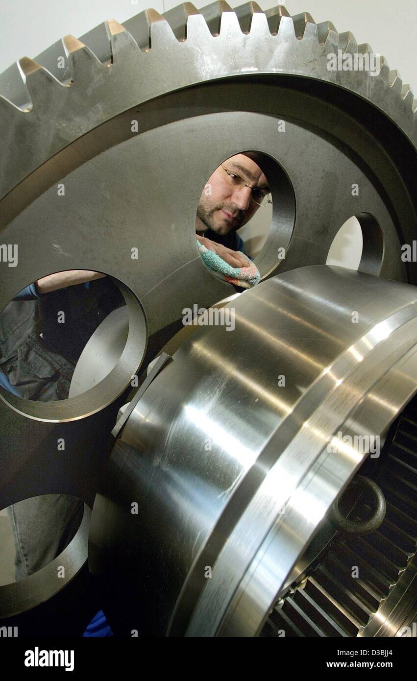 (dpa) - A man looks through the recesses of a precision cog wheel at ...