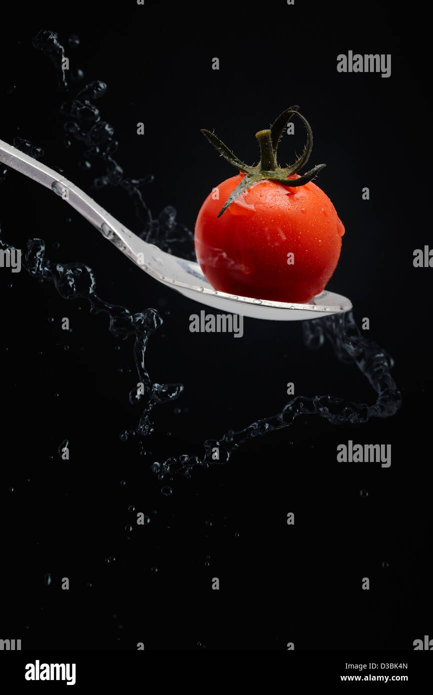 Teaspoon with red cherry tomato and dripping natural mineral water in ...