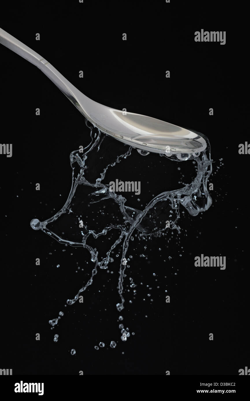 Teaspoon with dripping natural mineral water in black black-ground ...