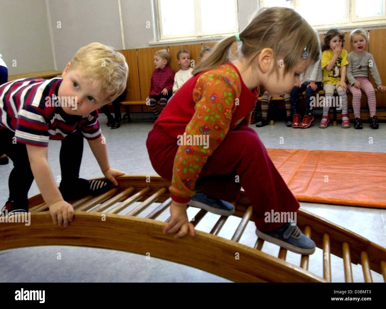 (dpa) - Two children climbe across a bend stepping ladder while a ...