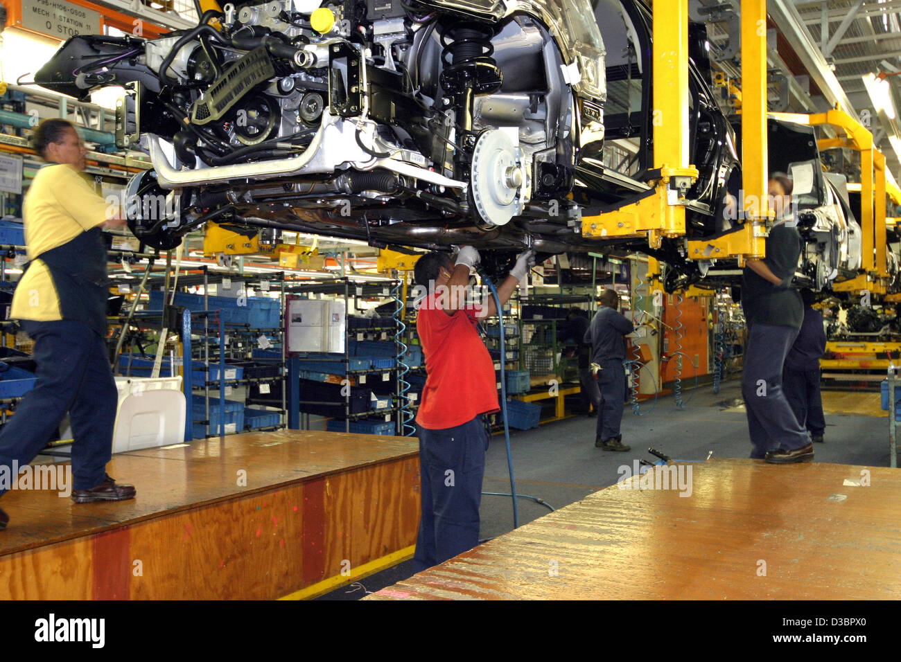 (dpa) - Employees work on a car at the DaimlerChrysler production plant ...