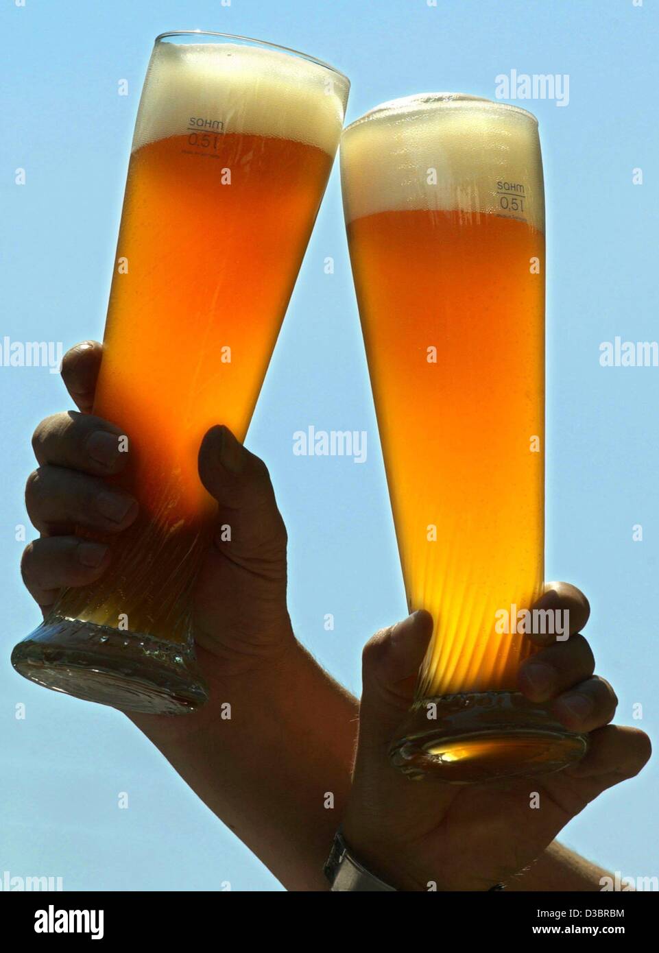 (dpa files) - Two men clink their beer glasses in a beer garden in ...