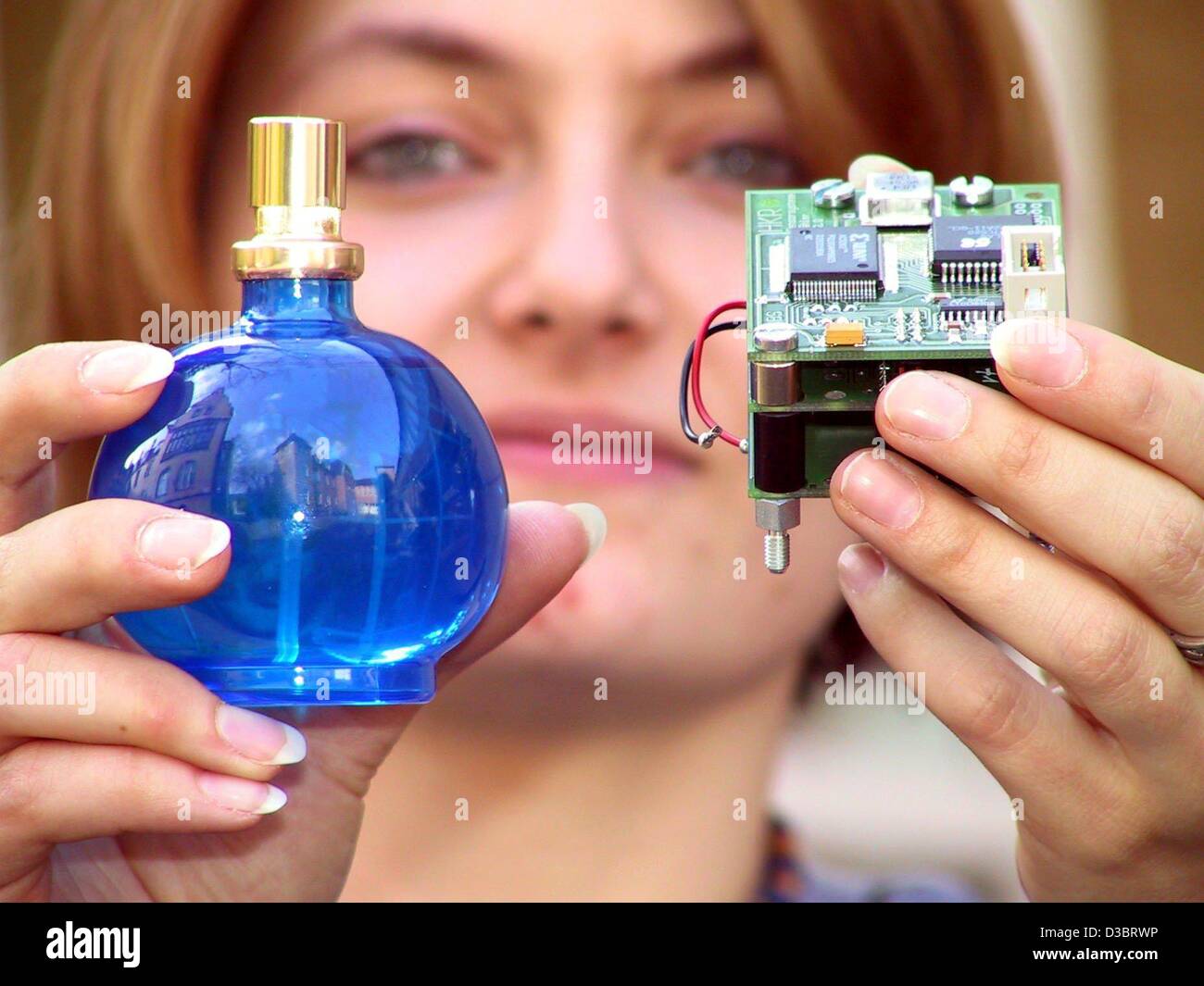 (dpa) - A young woman shows a fragrance in a blue bottle and a ...