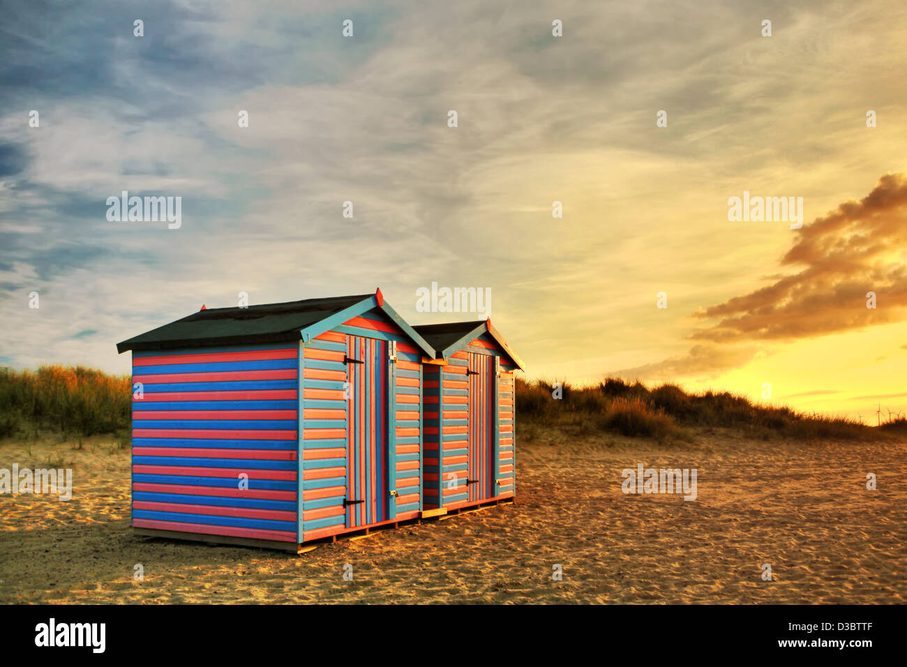 A golden sunrise illuminates traditional British beach huts at Great ...