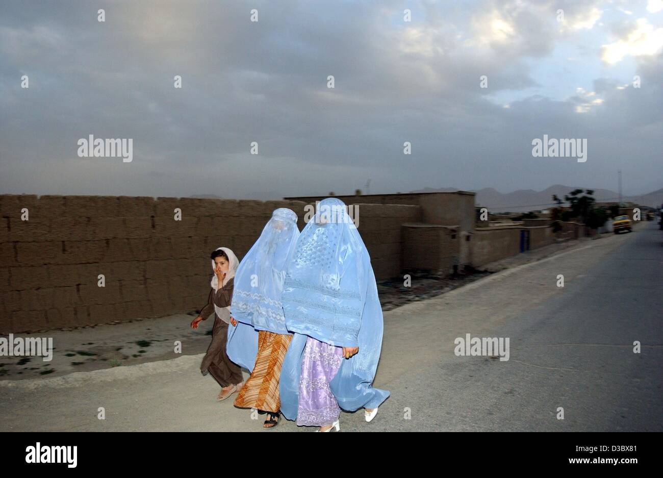(dpa) - Two women wearing the traditional blue burka veil walk with a ...