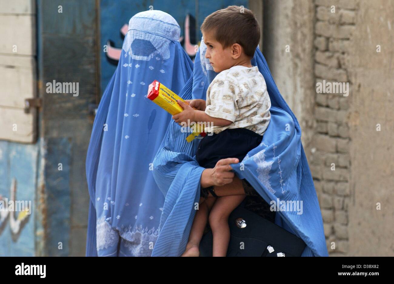 (dpa) - Two women wearing the traditional blue burka veil carry a child ...