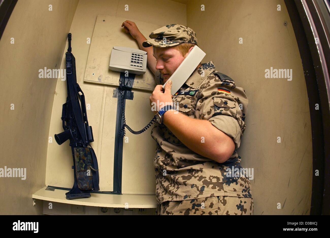(dpa) - A German soldier stands in a makeshift telephone booth and ...