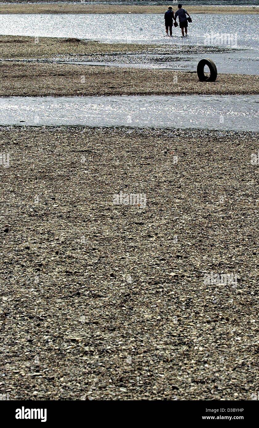 Two people wade through the low water in the almost dried out river bed ...