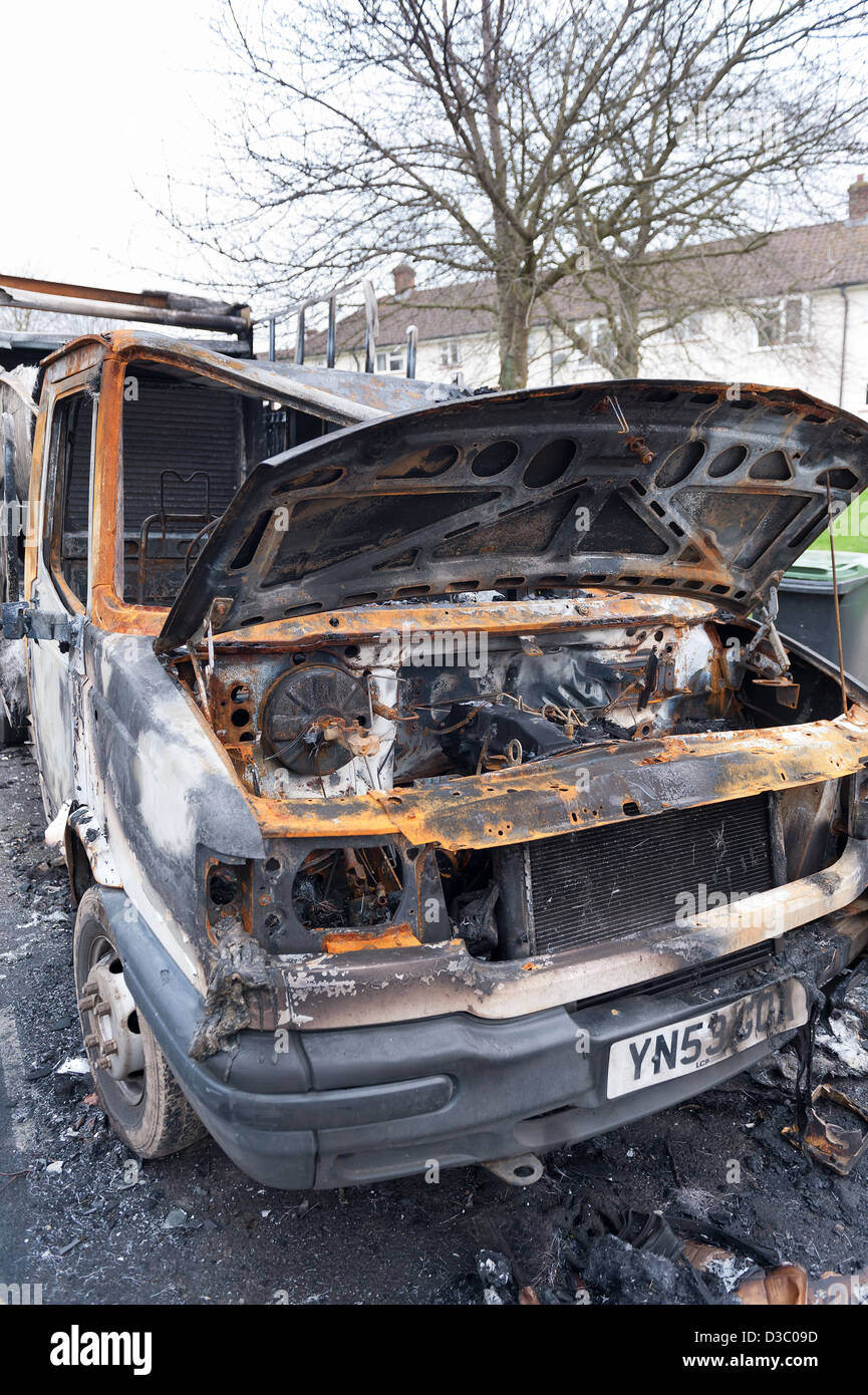 burnt vandalized van near end of grass verge footpath leading to white ...