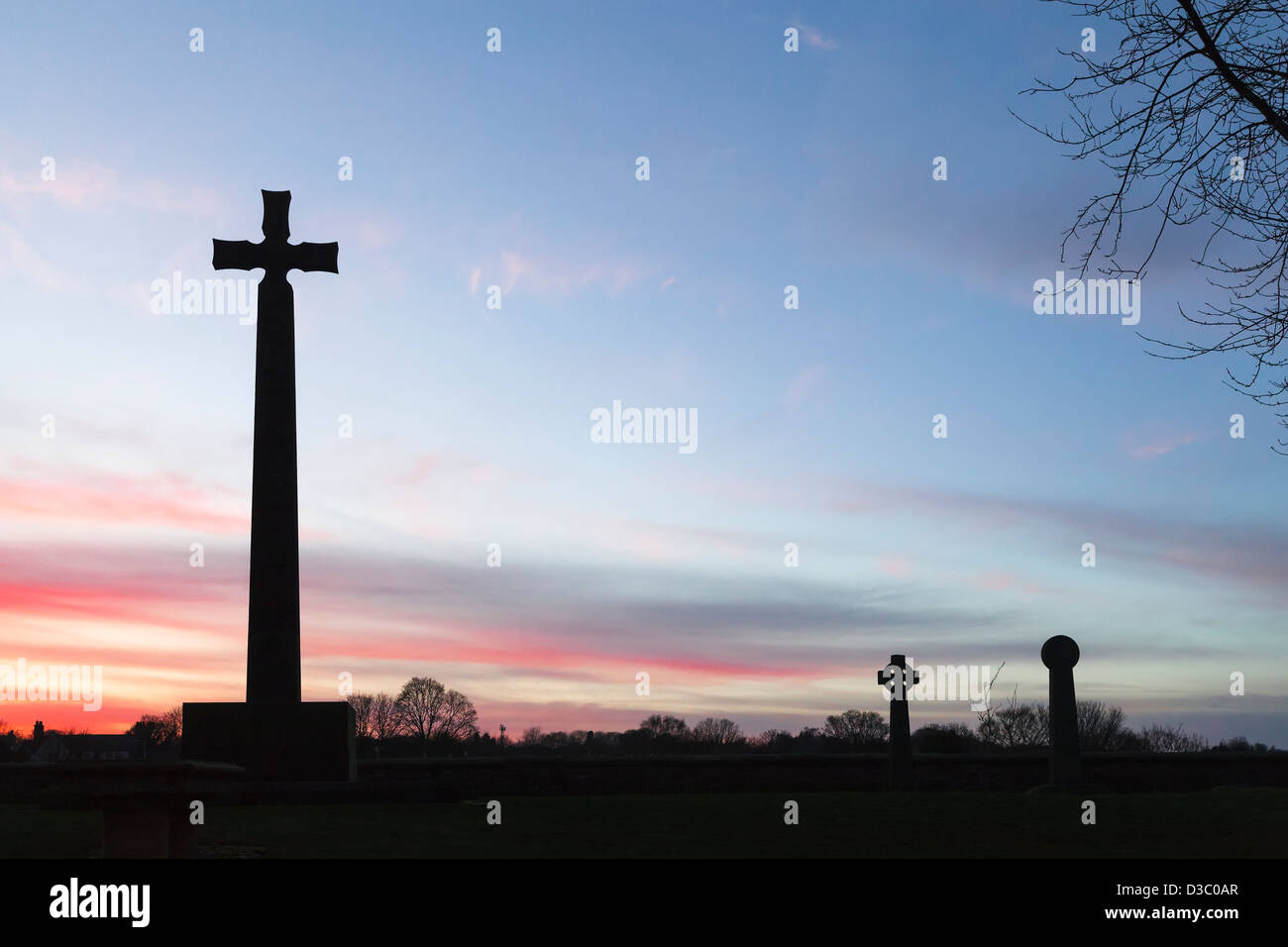 Silhouetted stone cross and Celtic standing stones at sunset next to ...