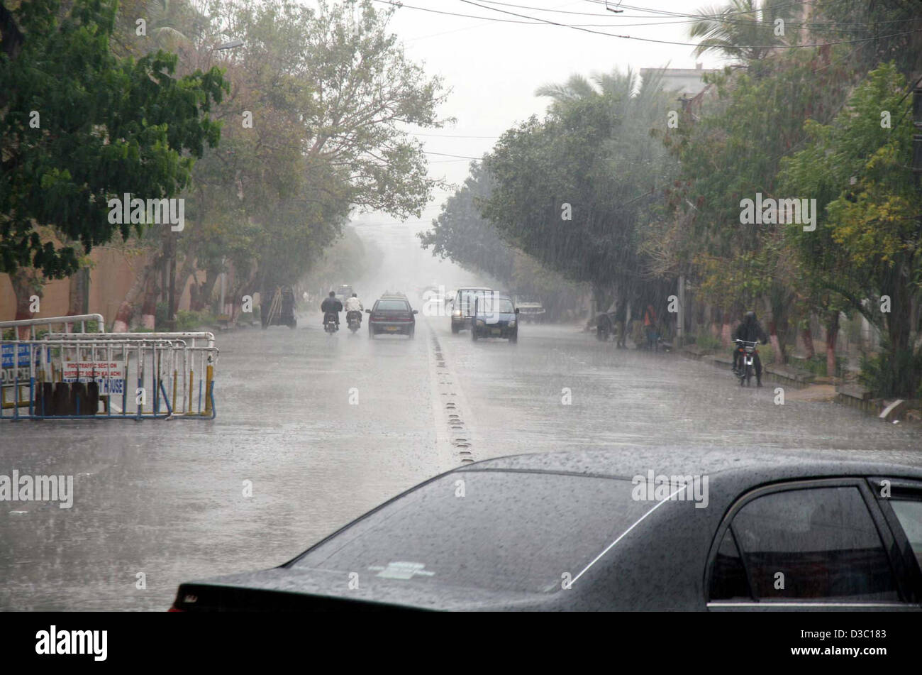 Commuters pass through a road during heavy downpour of winter season at ...