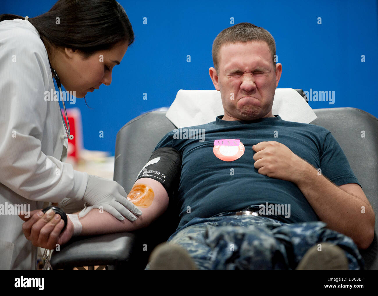 US Navy Seaman Sean Perkins grimaces as he donates blood during a Red ...