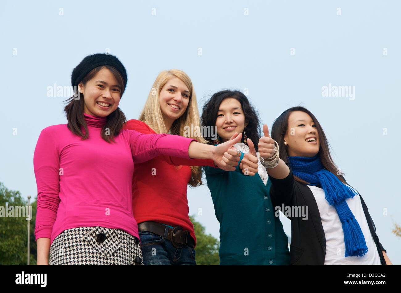 Group of 4 female students outdoor thumbs up Stock Photo - Alamy