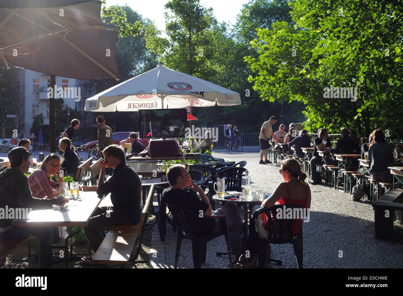Berlin, Germany, guests sit in a street cafe in the evening sun at ...