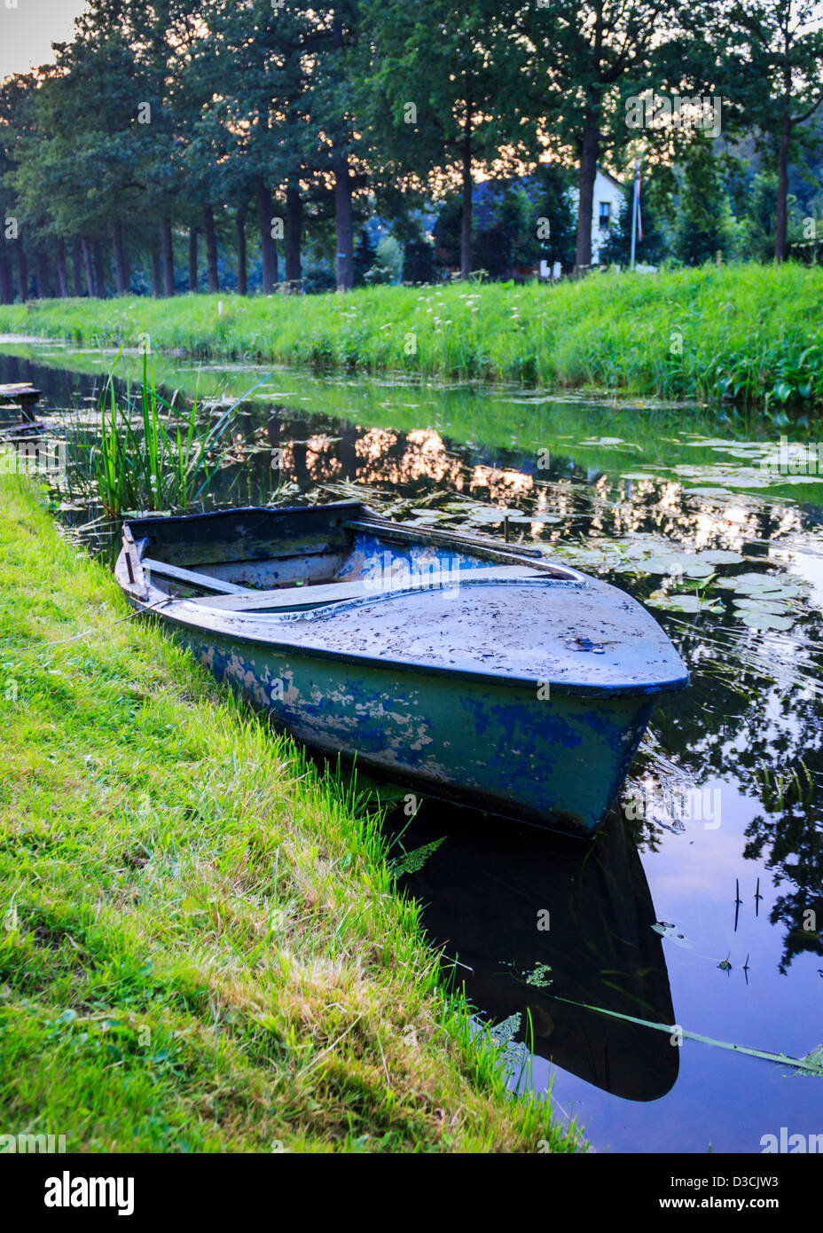 A worn and decrepit rowboat floats in a canal in the Netherlands ...