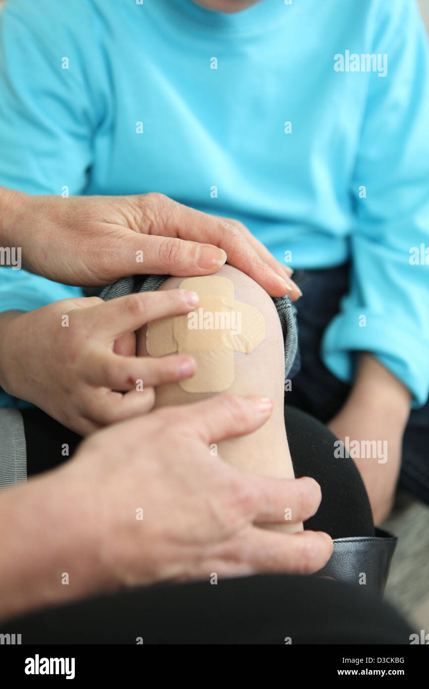 An adult putting a plaster on a child's knee Stock Photo - Alamy