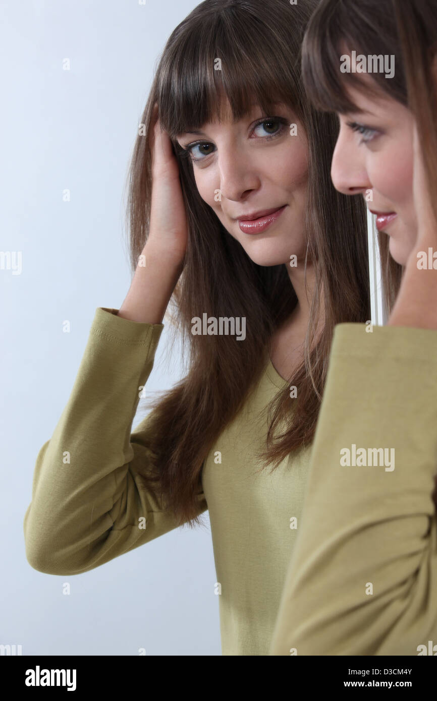 An attractive woman looking at her reflection in the mirror Stock Photo ...