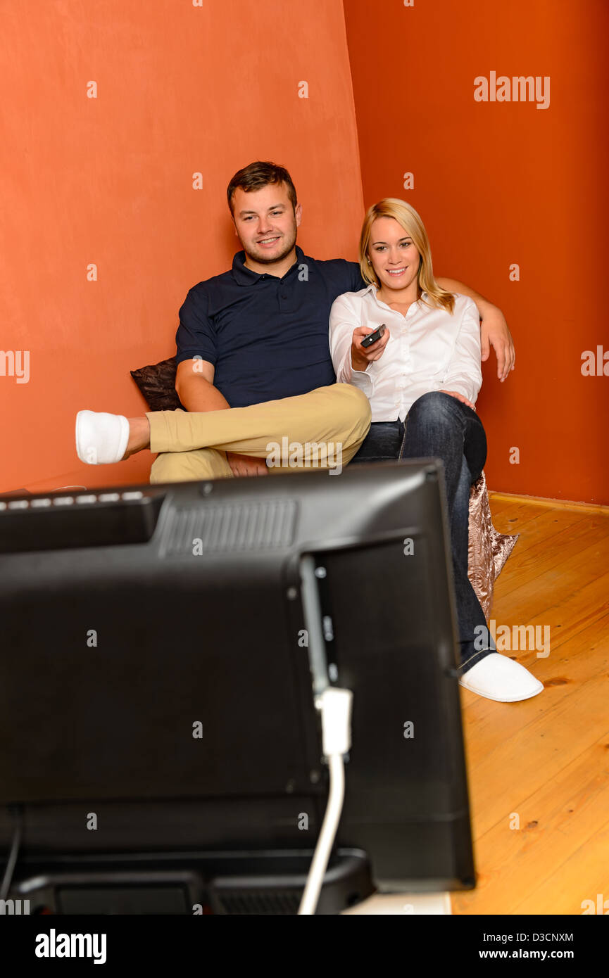 Smiling couple changing channels watching television evening using ...