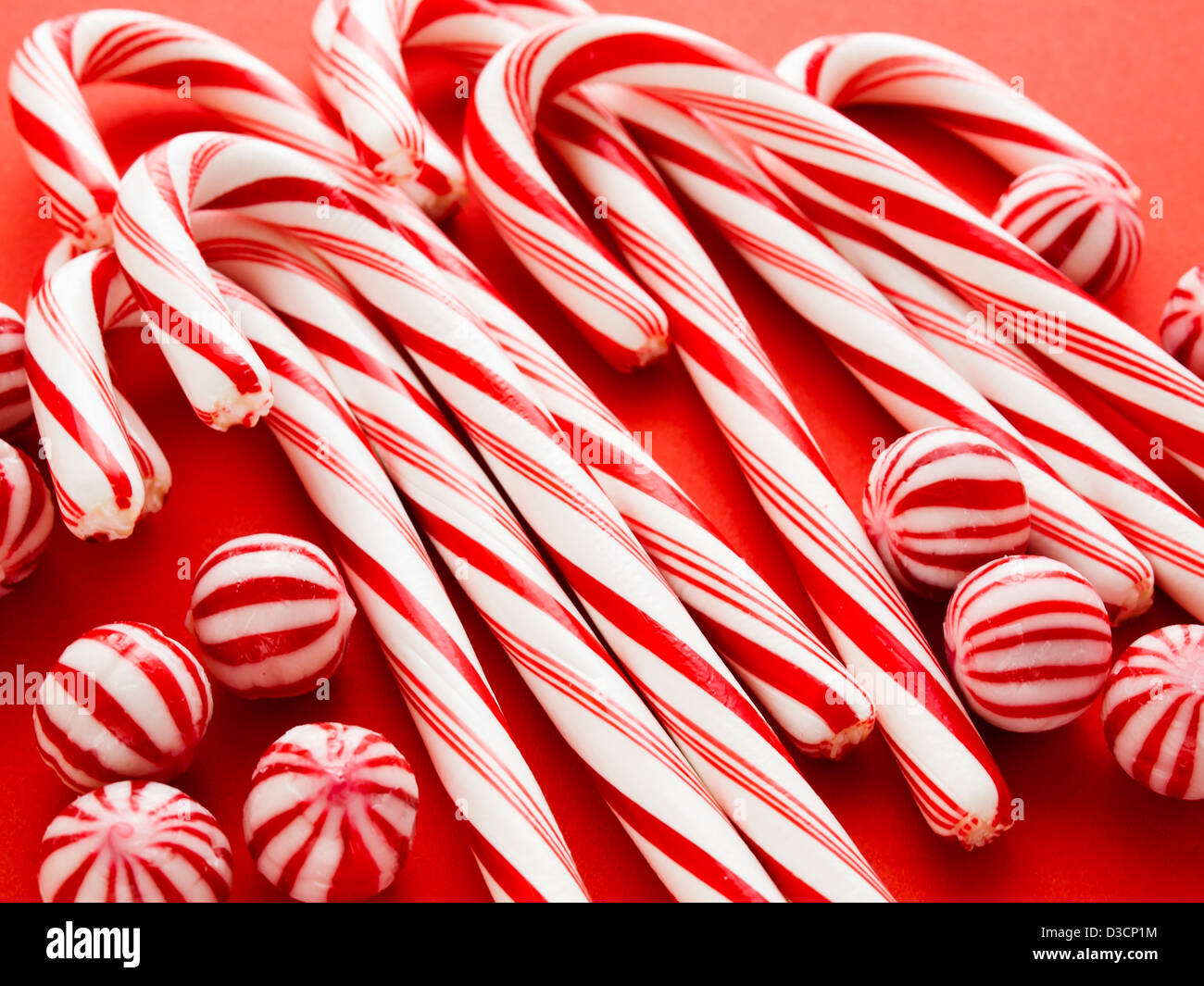 White and red peppermint candy canes on red background Stock Photo - Alamy