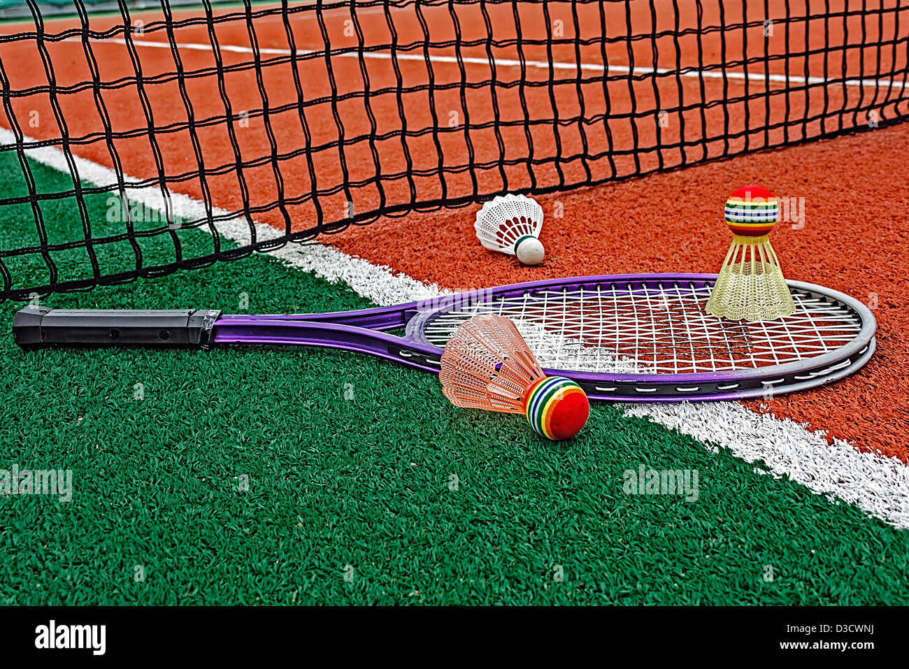 Shuttlecock and badminton racket arranged around the net on a synthetic ...