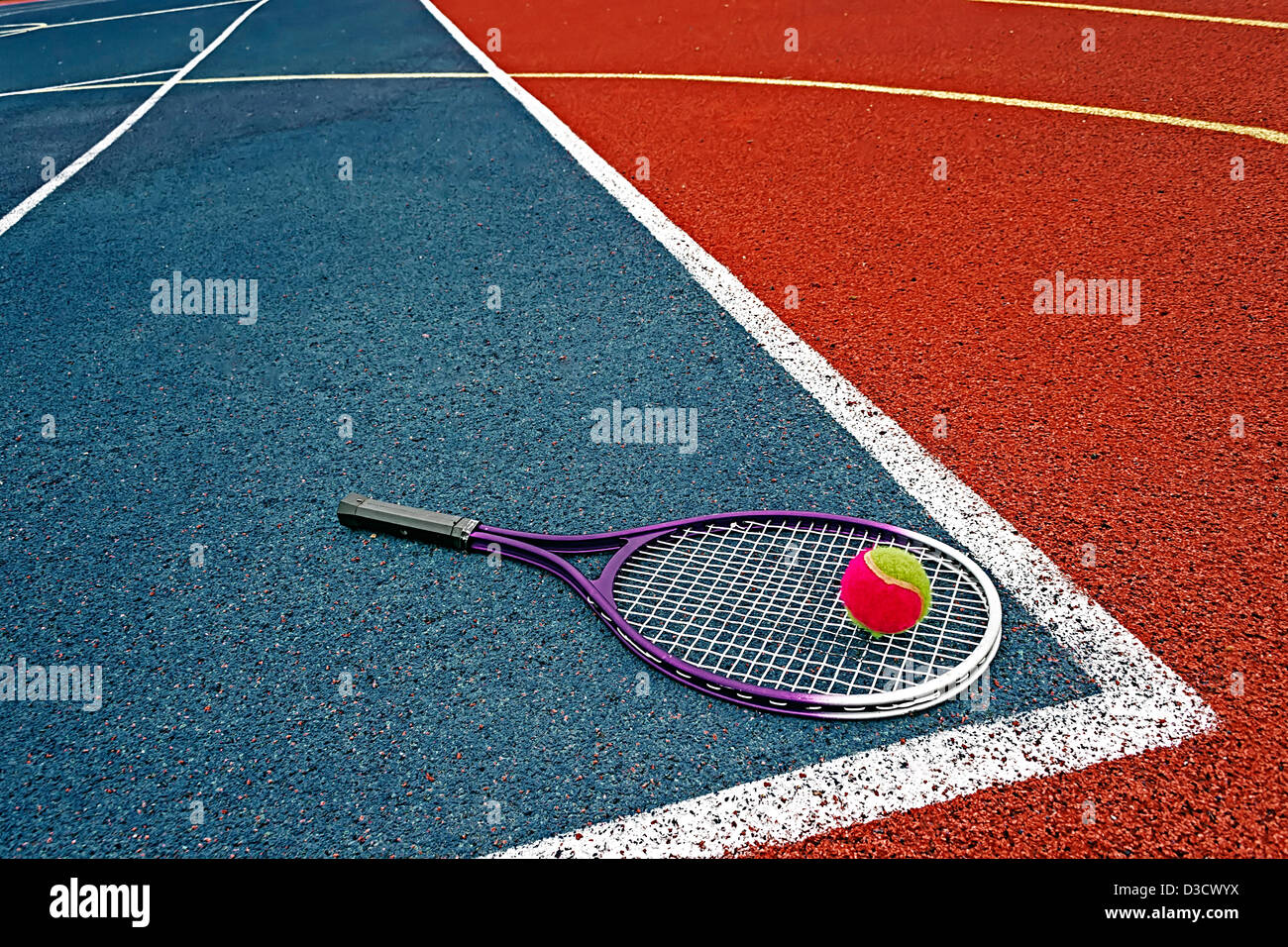 Tennis colored ball and racket, placed in the corner of a synthetic ...