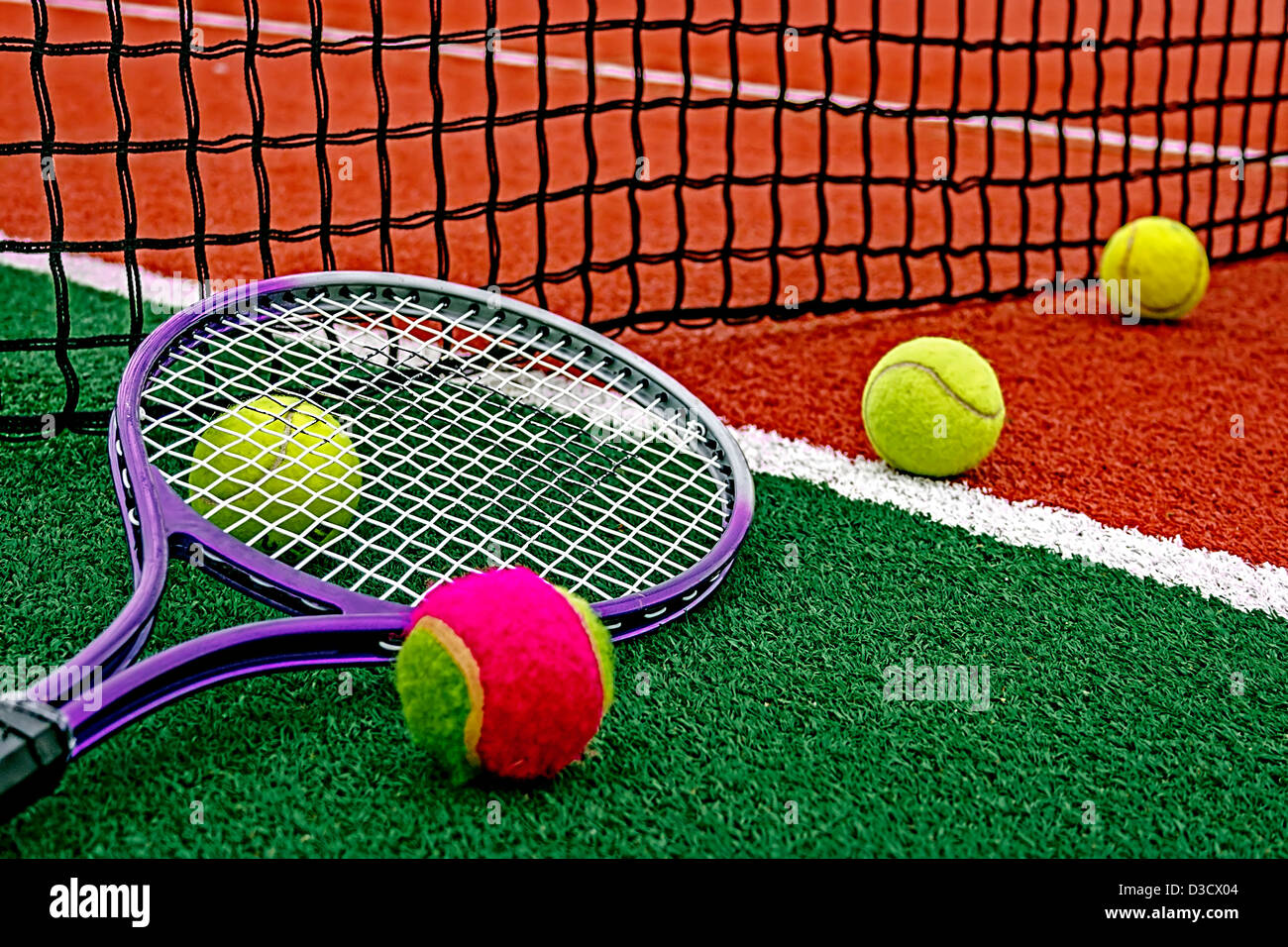 Ball and tennis racket arranged around the net on a synthetic field ...