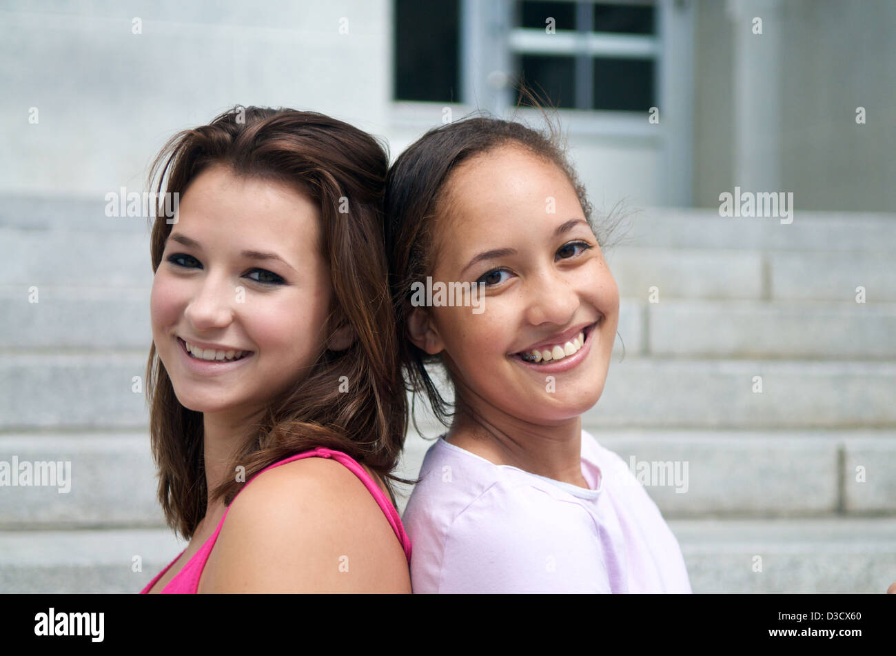Teenager friends smiling back to back Stock Photo - Alamy