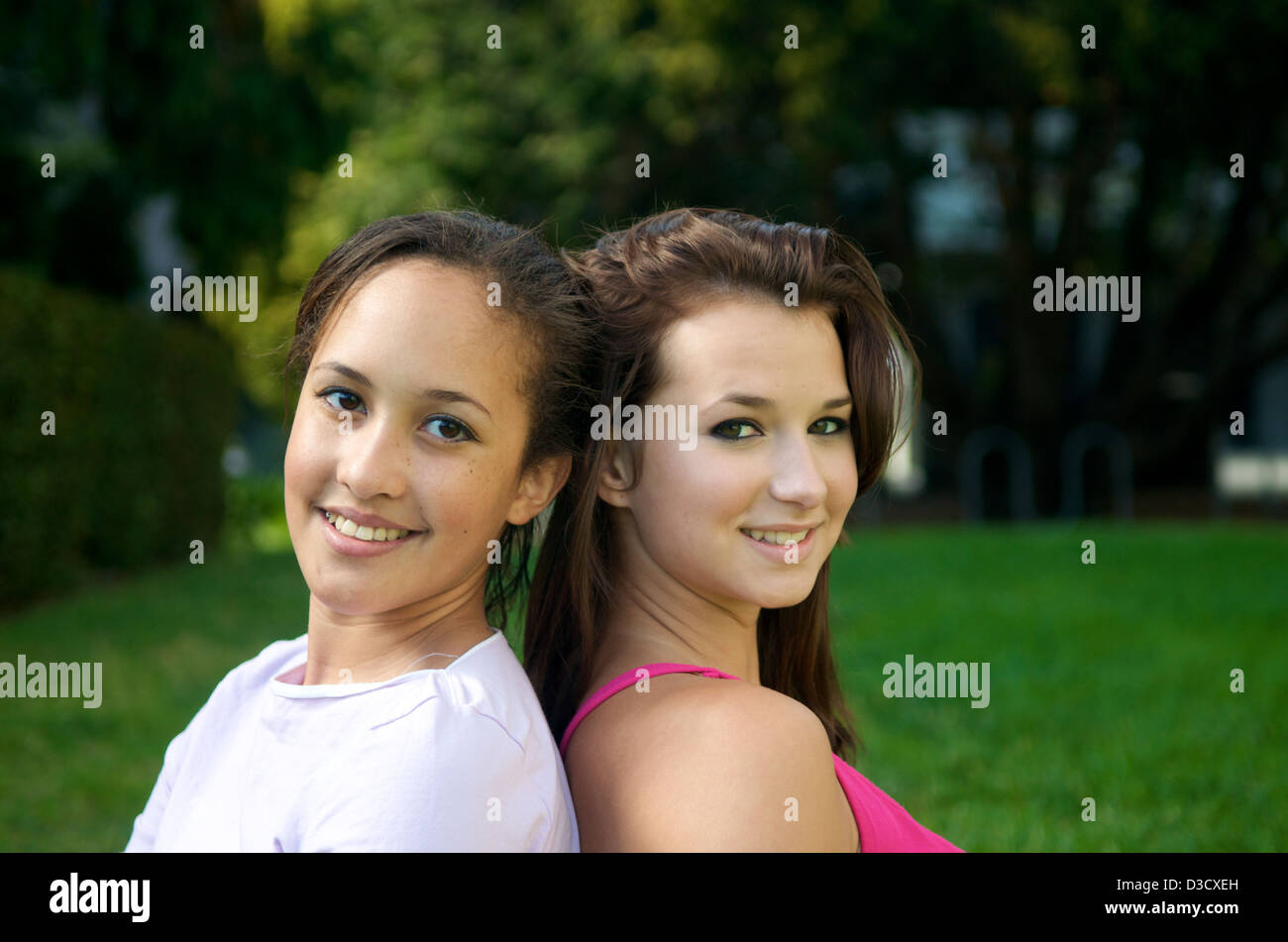 Teenager girl friends smiling back to back Stock Photo - Alamy