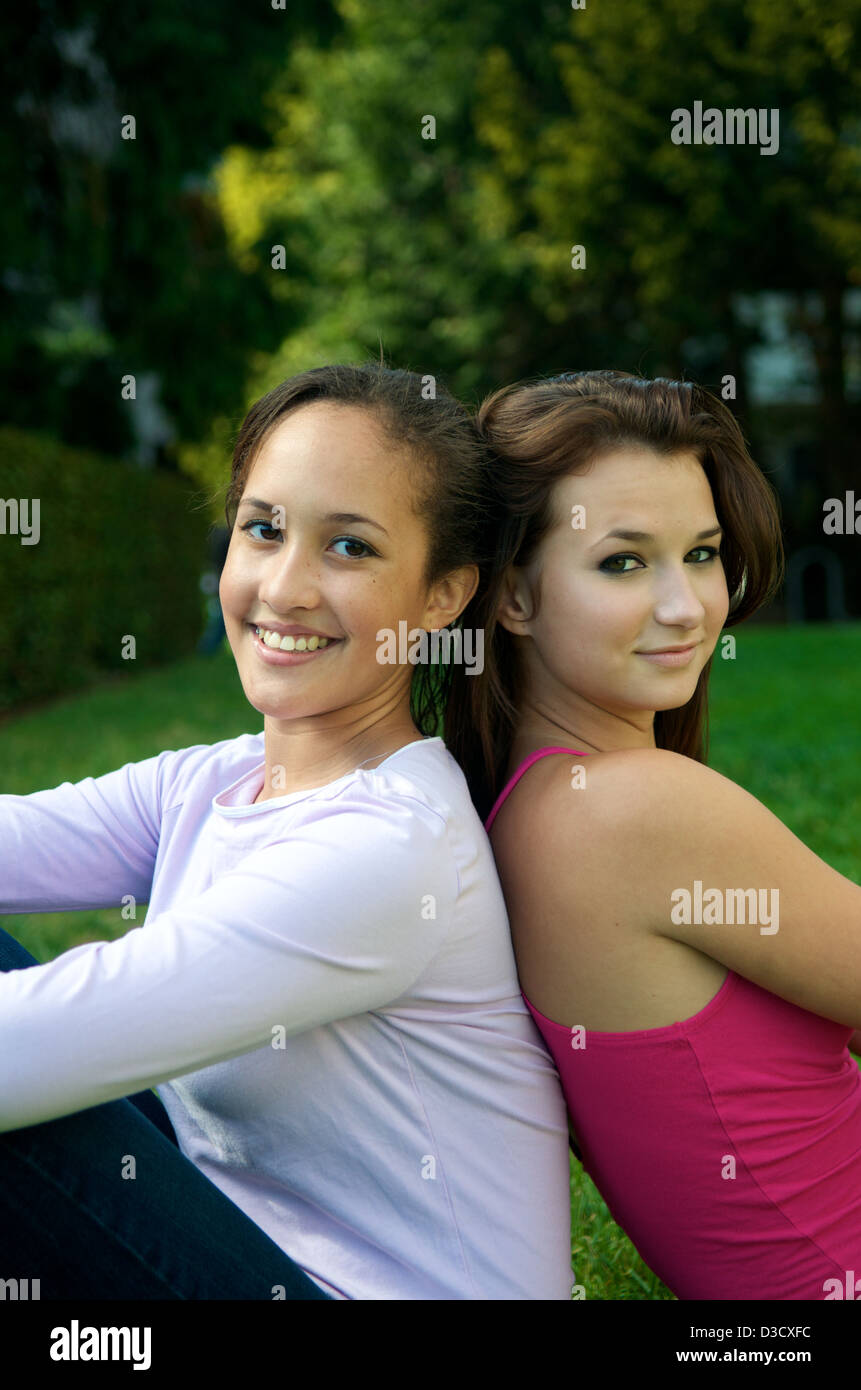 Teenager girl friends smiling back to back Stock Photo - Alamy
