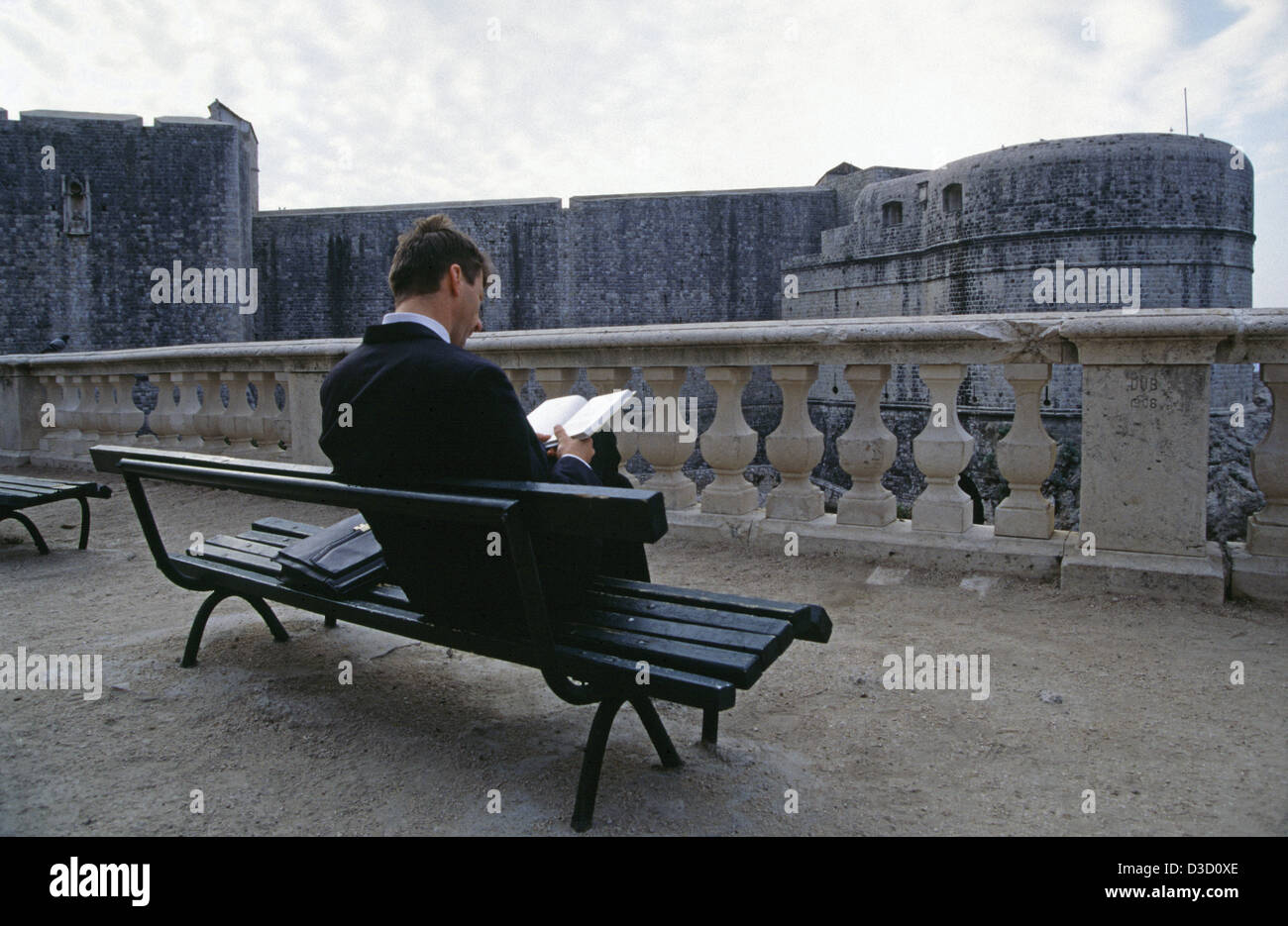 A Croatian man reading a book on the walled promenade of Stari Grad the ...