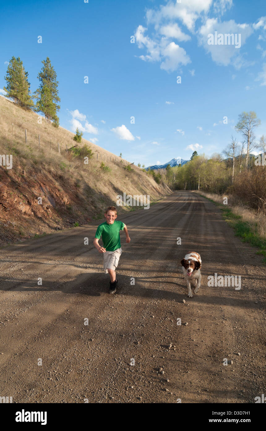 Boy running with dog on a rural road in Oregon's Wallowa Valley Stock ...
