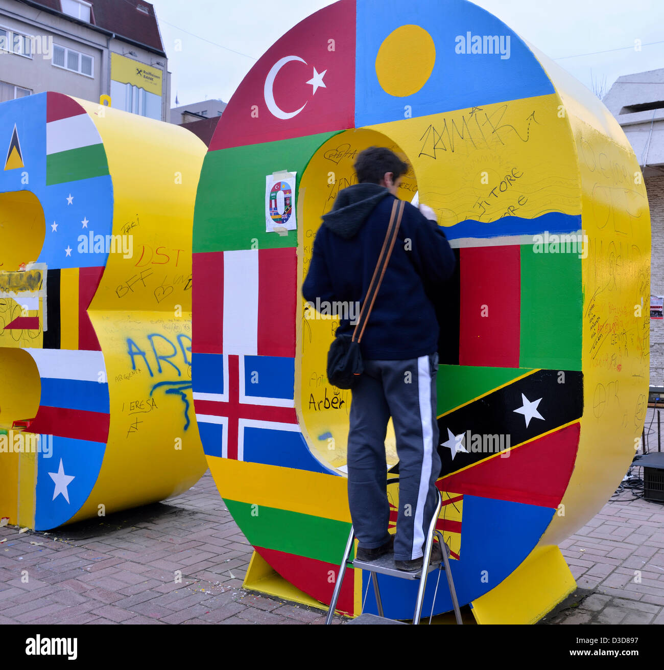 Young Kosovan people paint international flags on the outdoor sculpture ...
