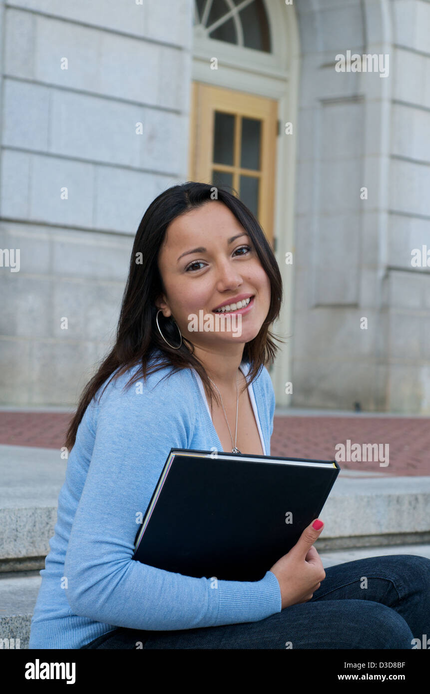 Hispanic female college student with textbook on university campus ...