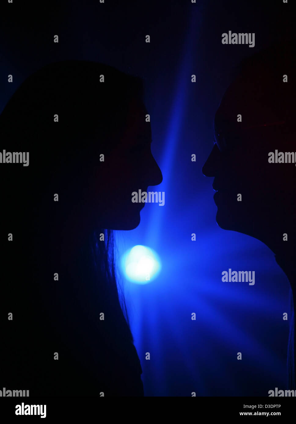 Two people in silhouette on a dark blue background Stock Photo - Alamy