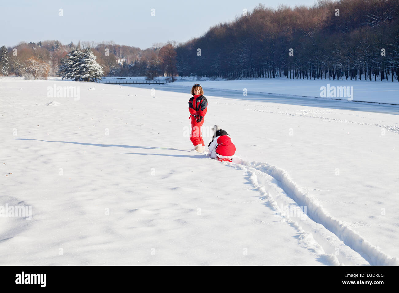 Middle aged woman pulling red sledge with her daughter across a snow ...