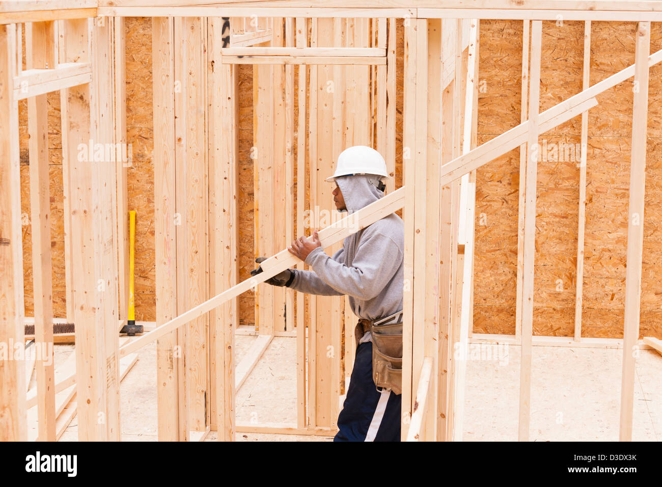 Carpenter carrying studs in framed house Stock Photo - Alamy
