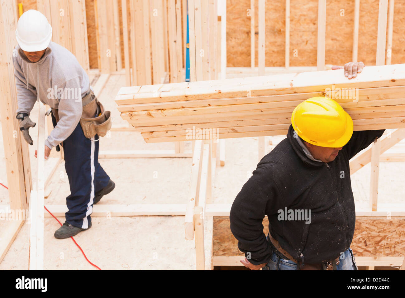 Carpenters carrying studs in a framed house Stock Photo - Alamy