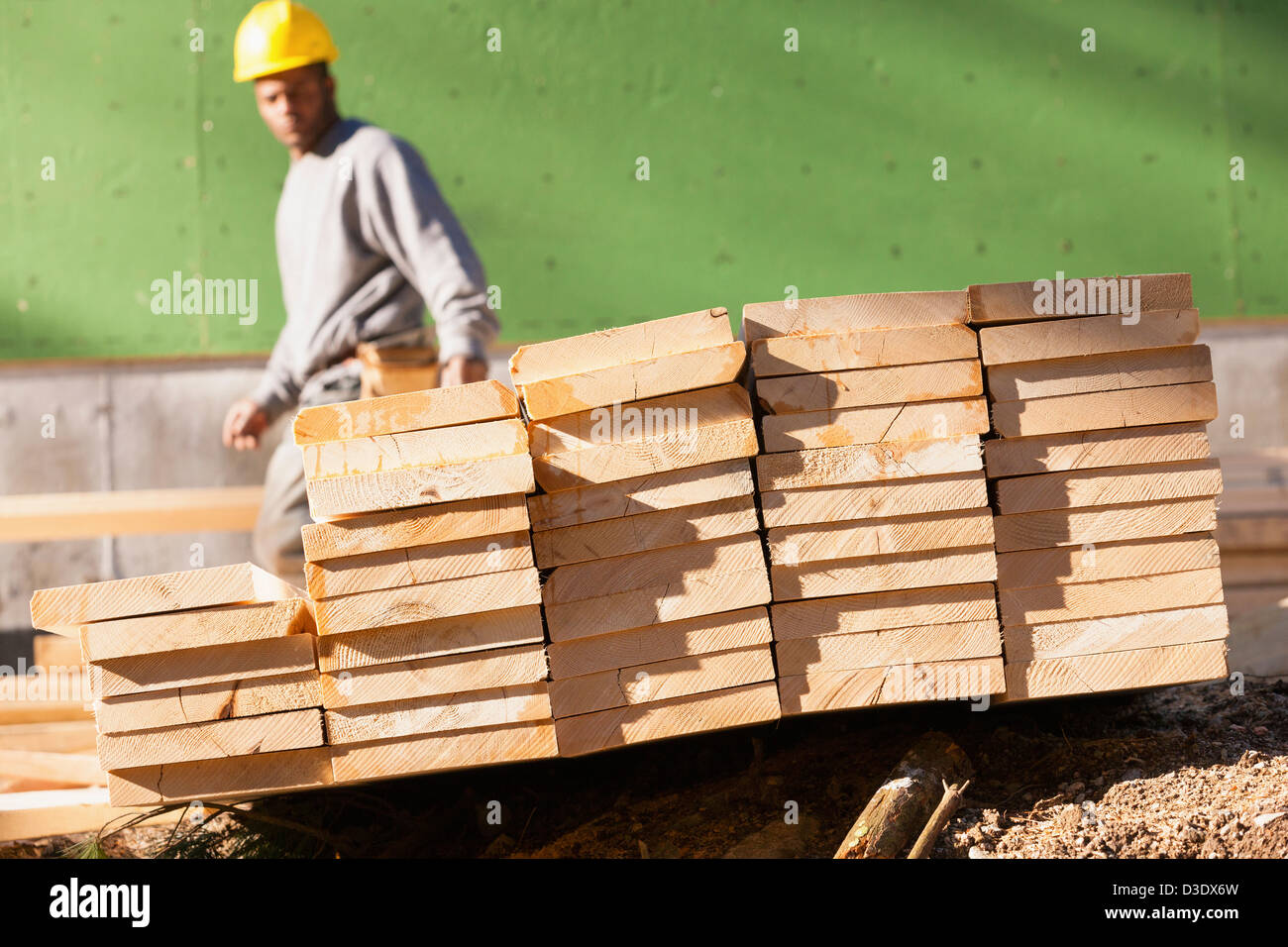 Stack of rafters with a carpenter in the background Stock Photo - Alamy