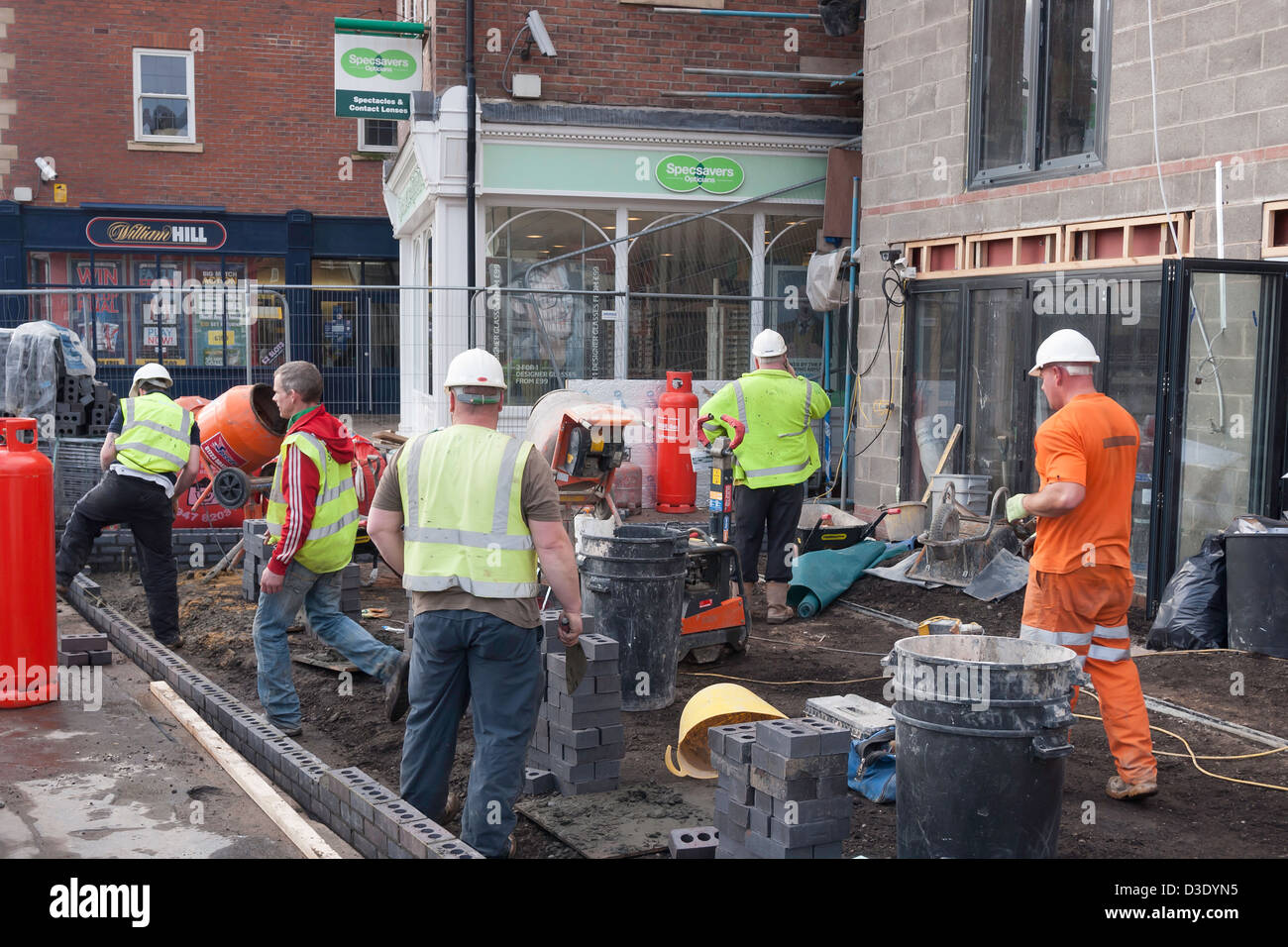 A busy building site with bricklayers building small walls and ...