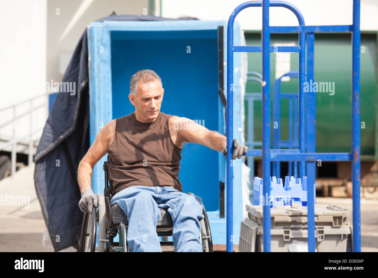 Loading dock worker with spinal cord injury in a wheelchair moving a ...