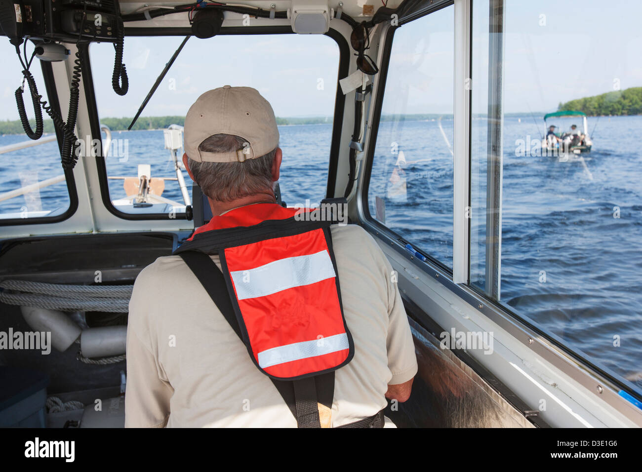 Public works engineer piloting service boat for sampling water on ...