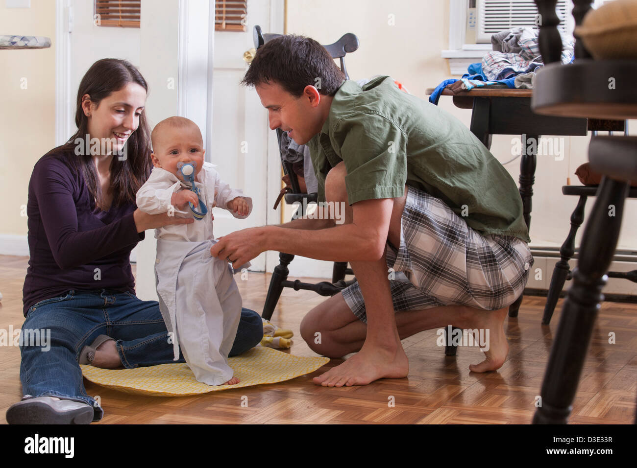 Parents changing their son's clothes together while sitting on the ...