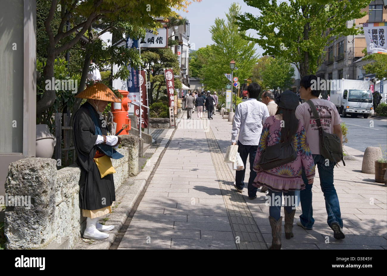 Tourists pass Buddhist monk begging for alms on Chuo-dori (Main Street ...