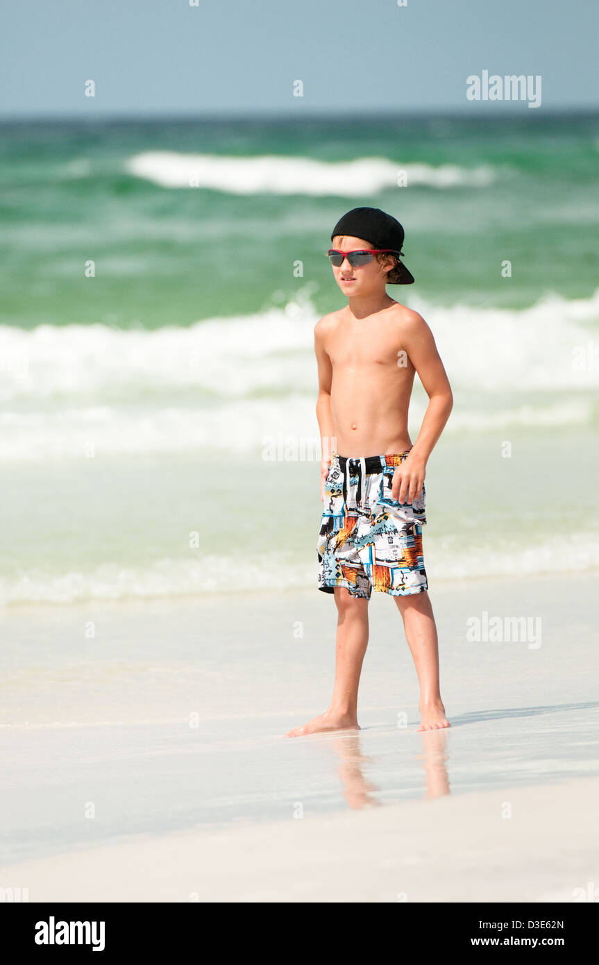 Young boy in Swim trunks at the beach with the ocean in the background ...